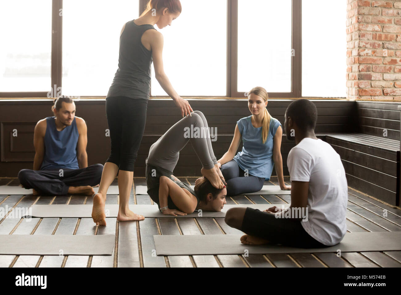 Female instructor helping with Ganda Bherundasana pose Stock Photo - Alamy