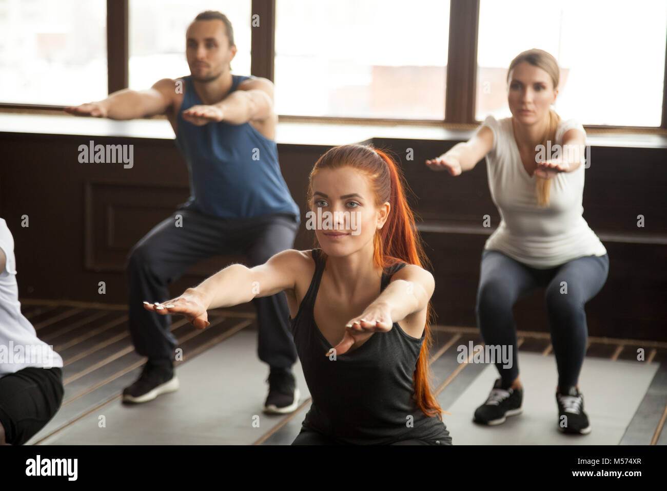 Sporty young people doing squat exercise at group fitness traini Stock ...