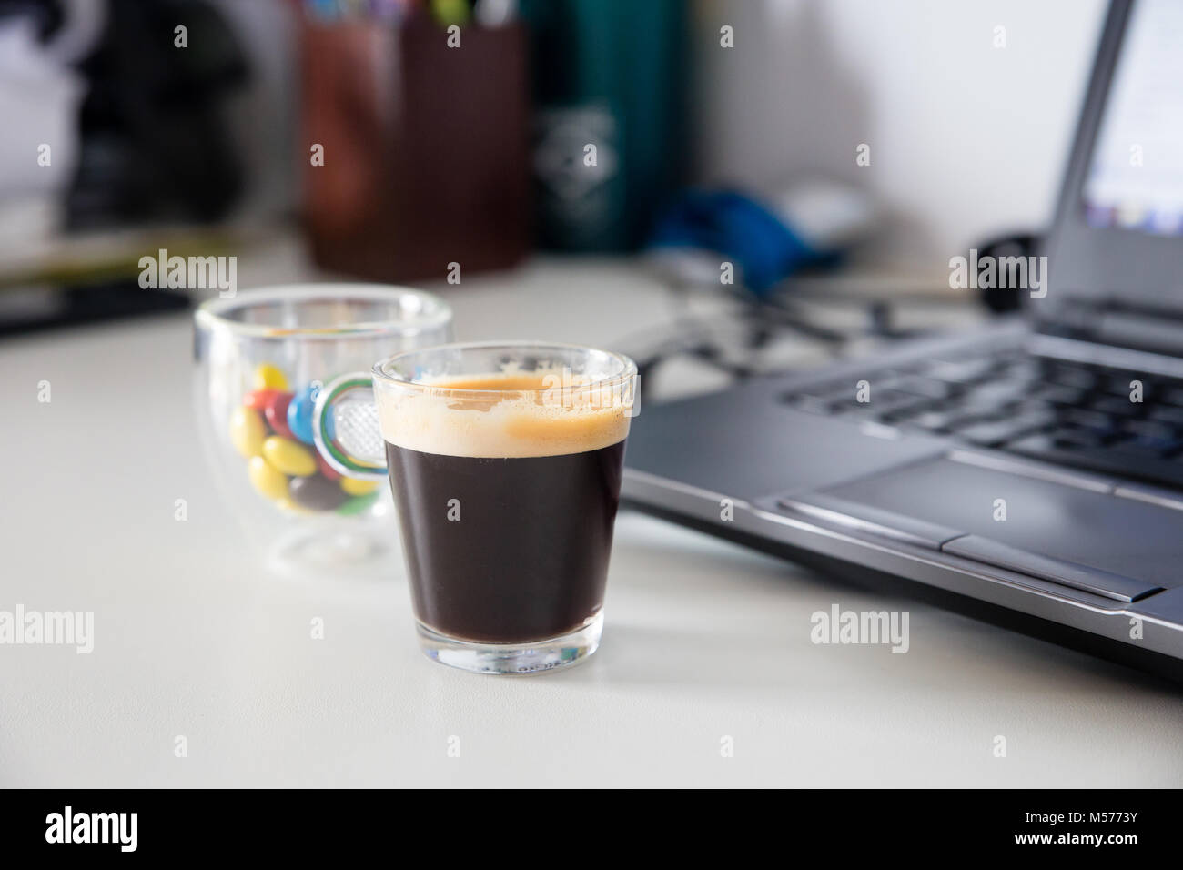 Cup of coffee and cup of colored chocolate filled sweets next to a ...