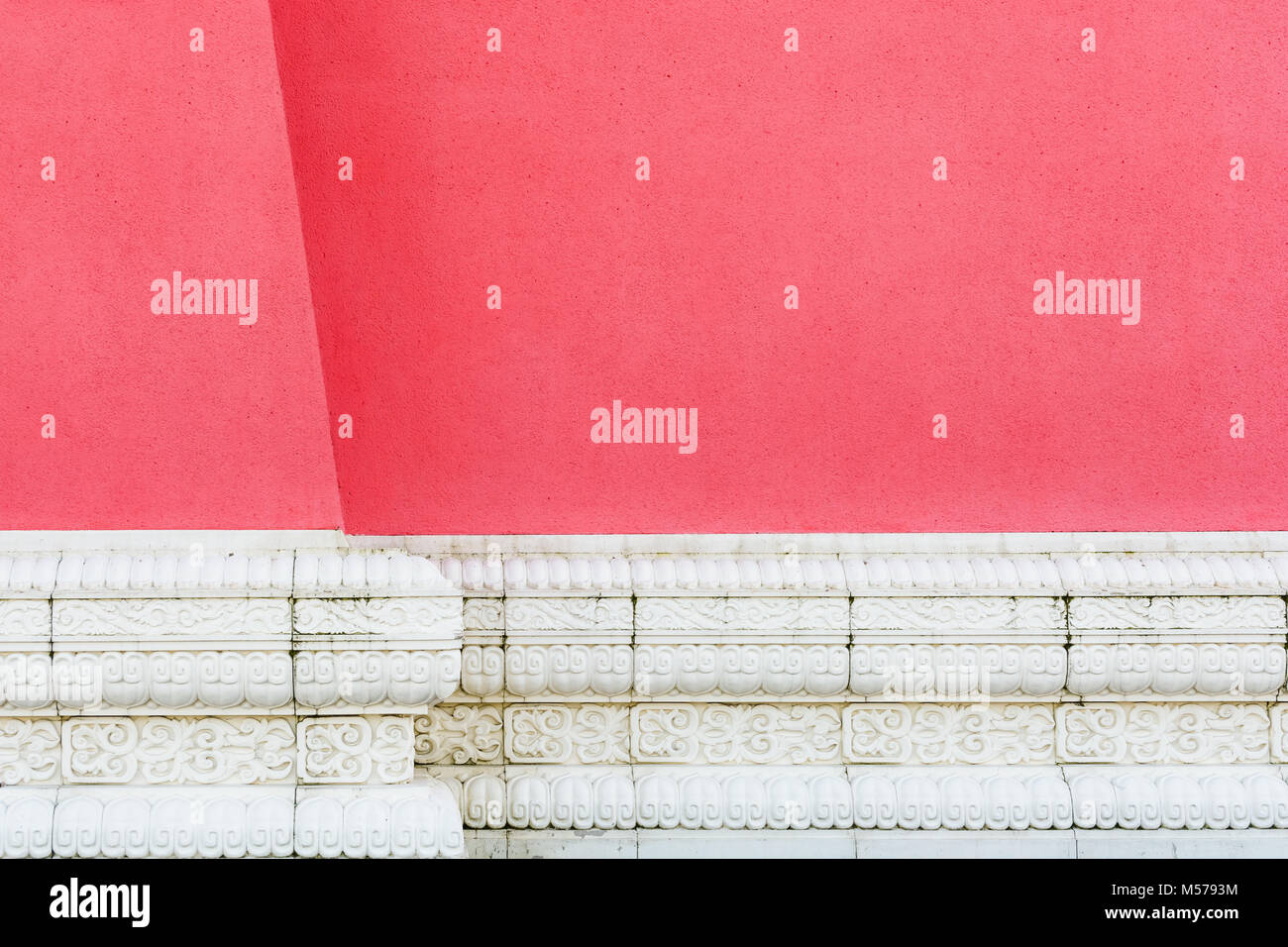 Front view of a red rendered wall with white carved cornice at the base ...