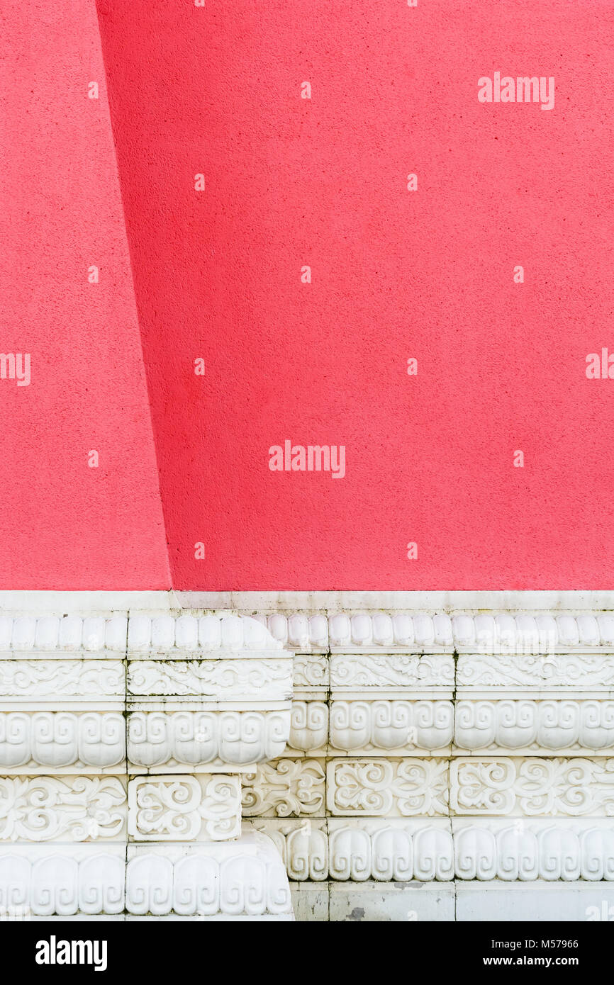 Front view of a red rendered wall with white carved cornice at the base ...