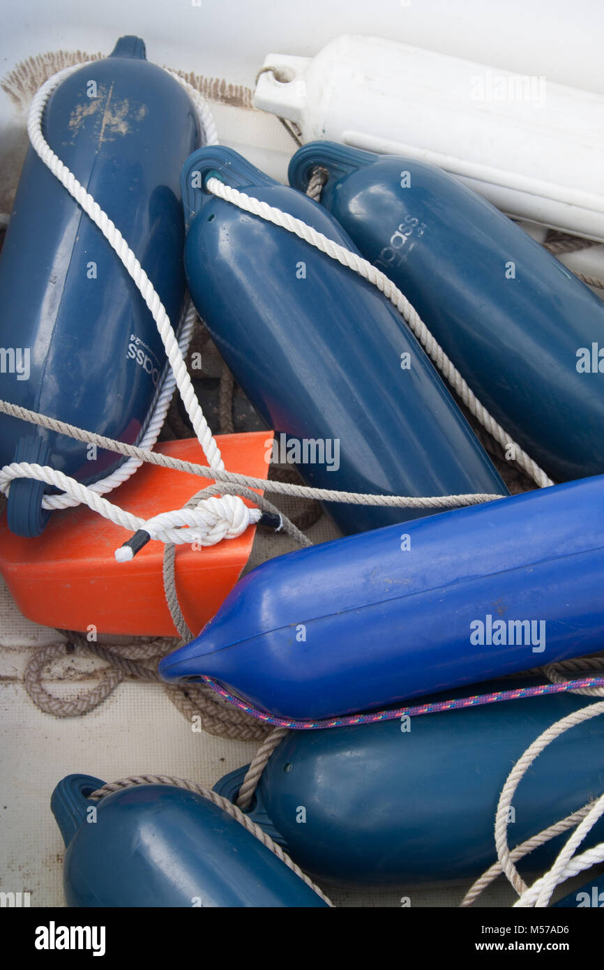 Blue and white bouy floats in white small fishing boat on mud at low ...