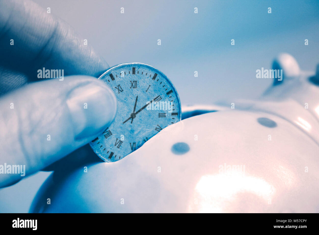 human fingers insert coin clock into piggy bank Stock Photo - Alamy