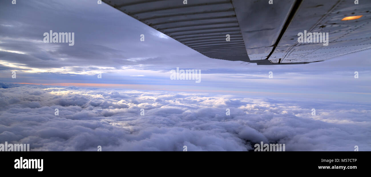 Flight over Alaska between clouds with sunrise Stock Photo - Alamy