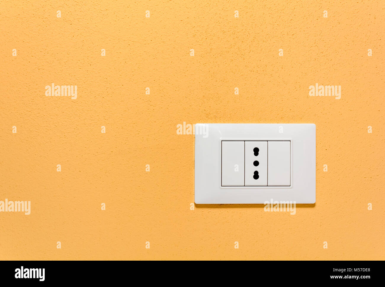 Empty wall socket on an orange interior wall Stock Photo - Alamy