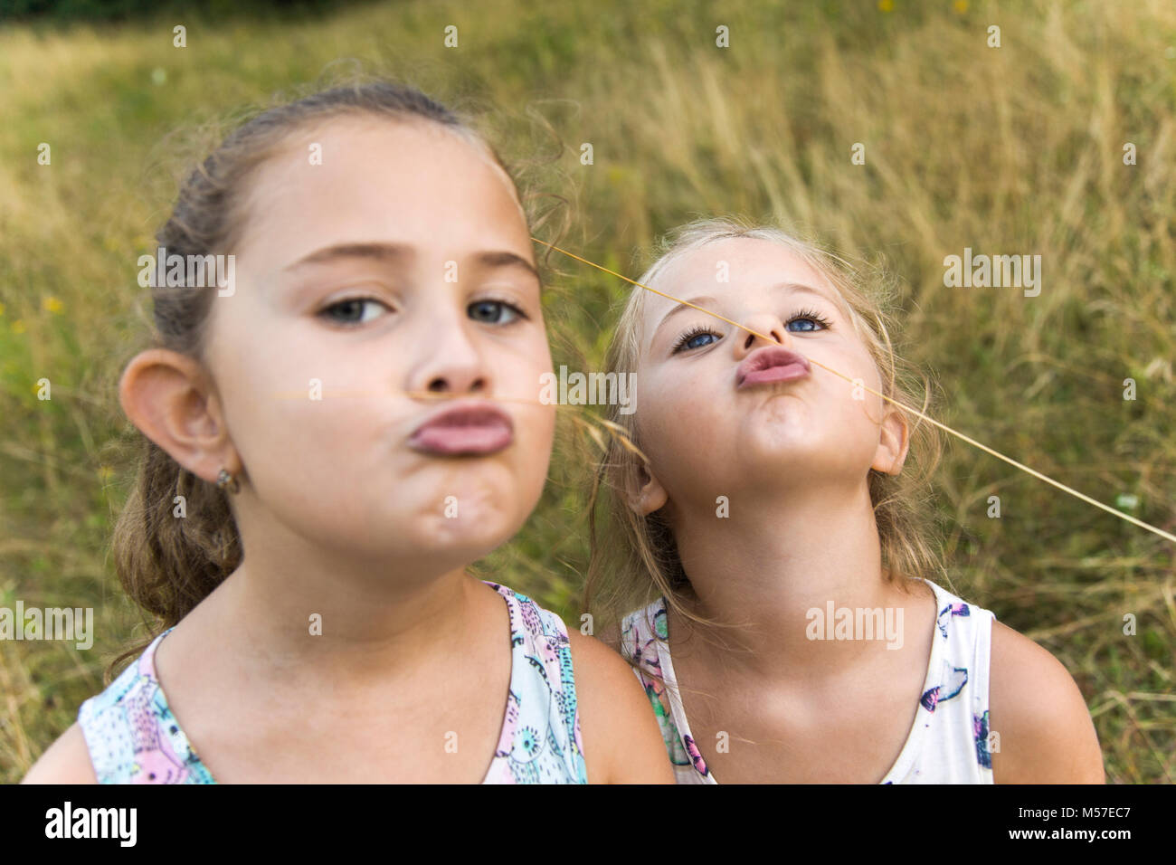 Two sisters playing - with one hand covers mouth of another, against ...
