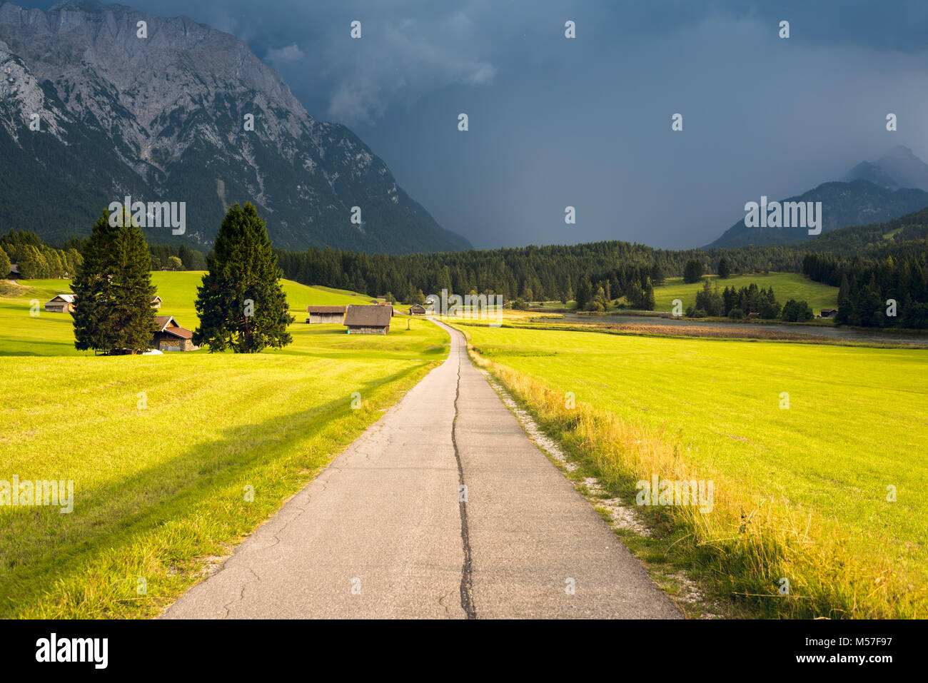 Sunlit country road in Alps, rain straight ahead Stock Photo - Alamy