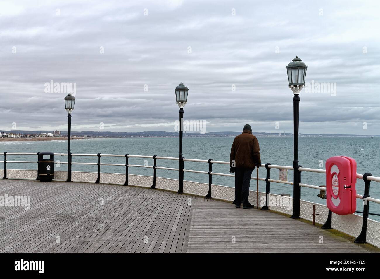 Rear view of a single old gentleman with walking stick looking out to ...