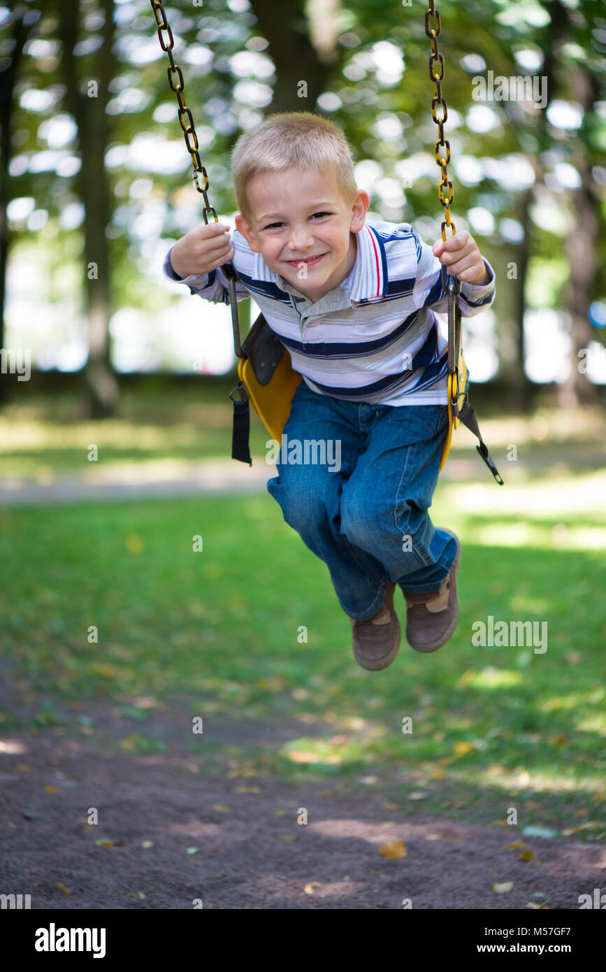 Cute little blond boy swinging on swings Stock Photo - Alamy