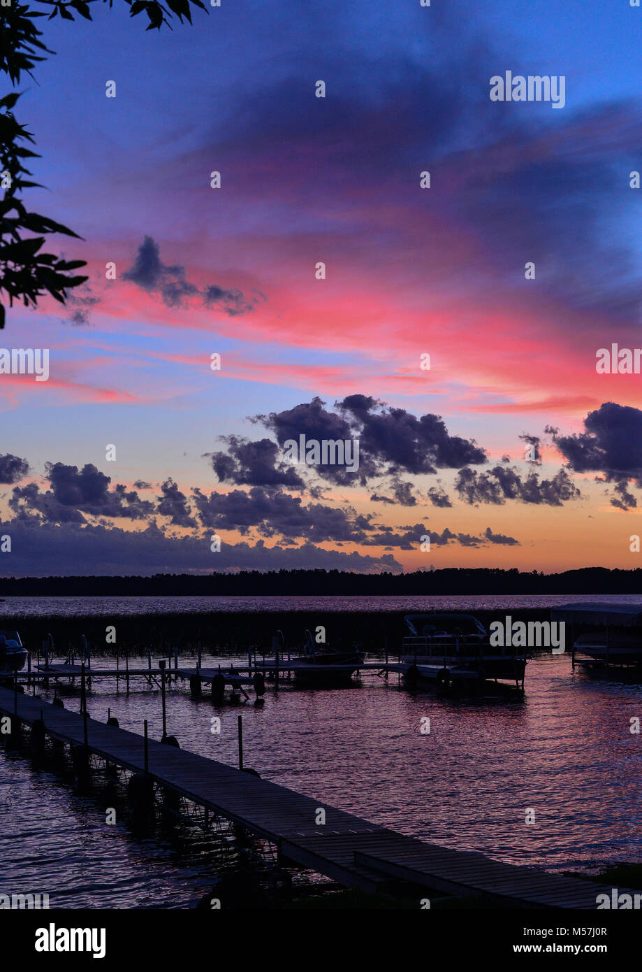 vertical image, vivid sunset on lake with dock and boats in vibrant ...