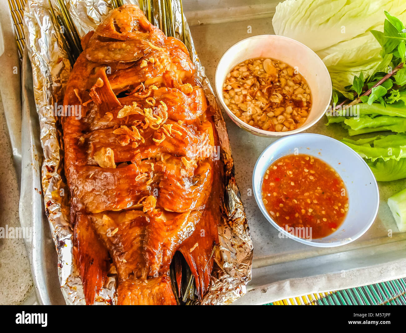 Red talapia fish grilled with herb in aluminium foil that ready to eat ...