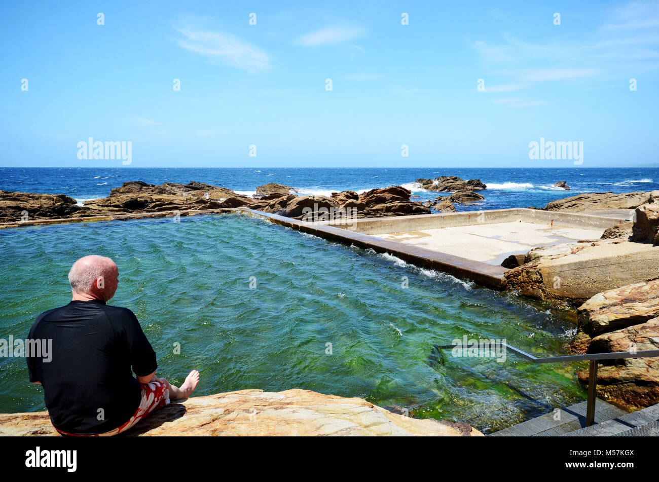 Man sitting on edge of pool at the Blue Pool Bermagui NSW Australia ...