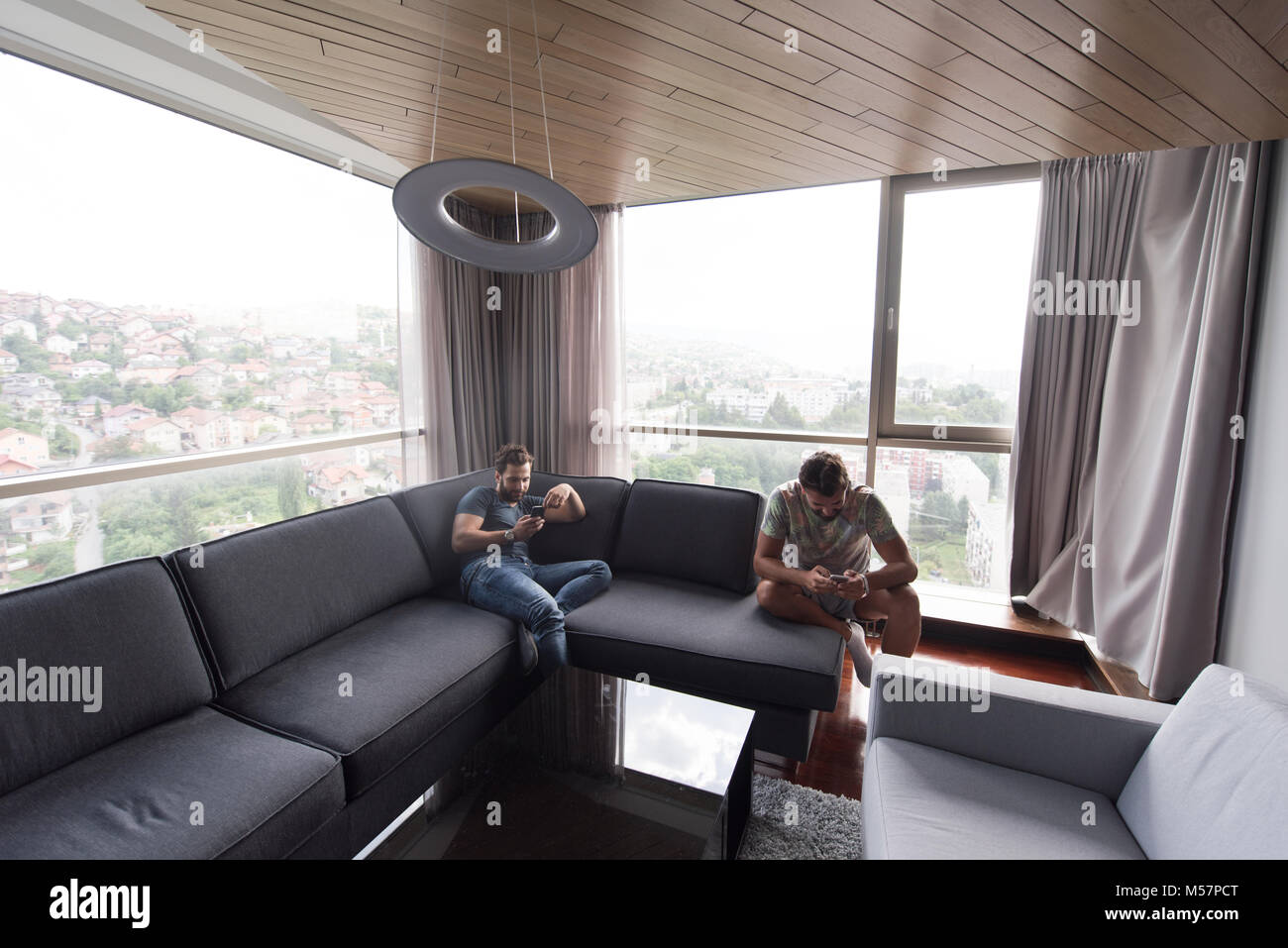 Handsome casual young men using a mobile phones near the window at home ...