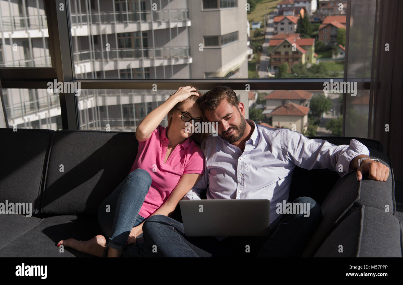 Young couple relaxing at home using laptop computers reading in the ...