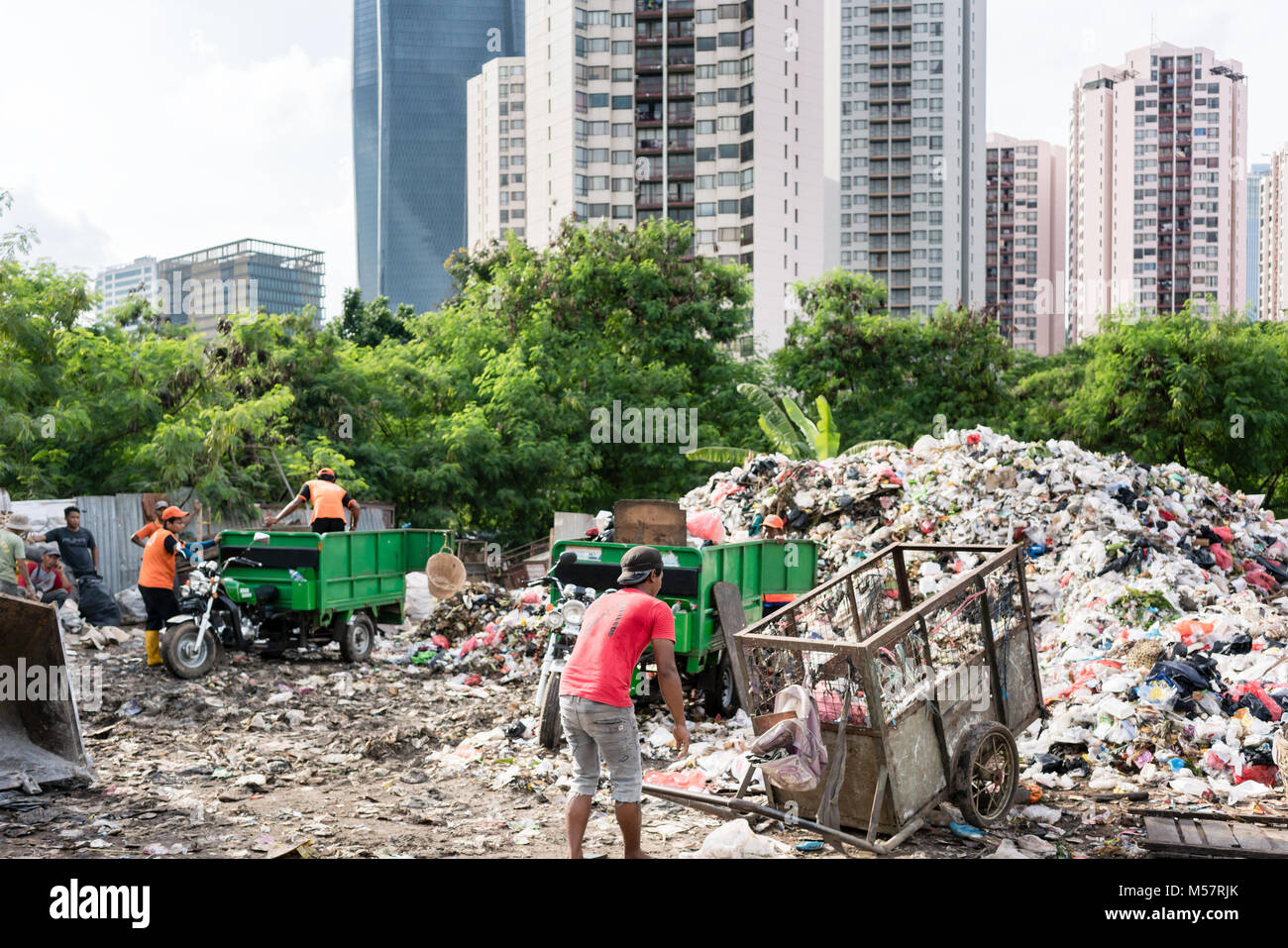 People disposing waste materials and garbage in a landfill site next to ...