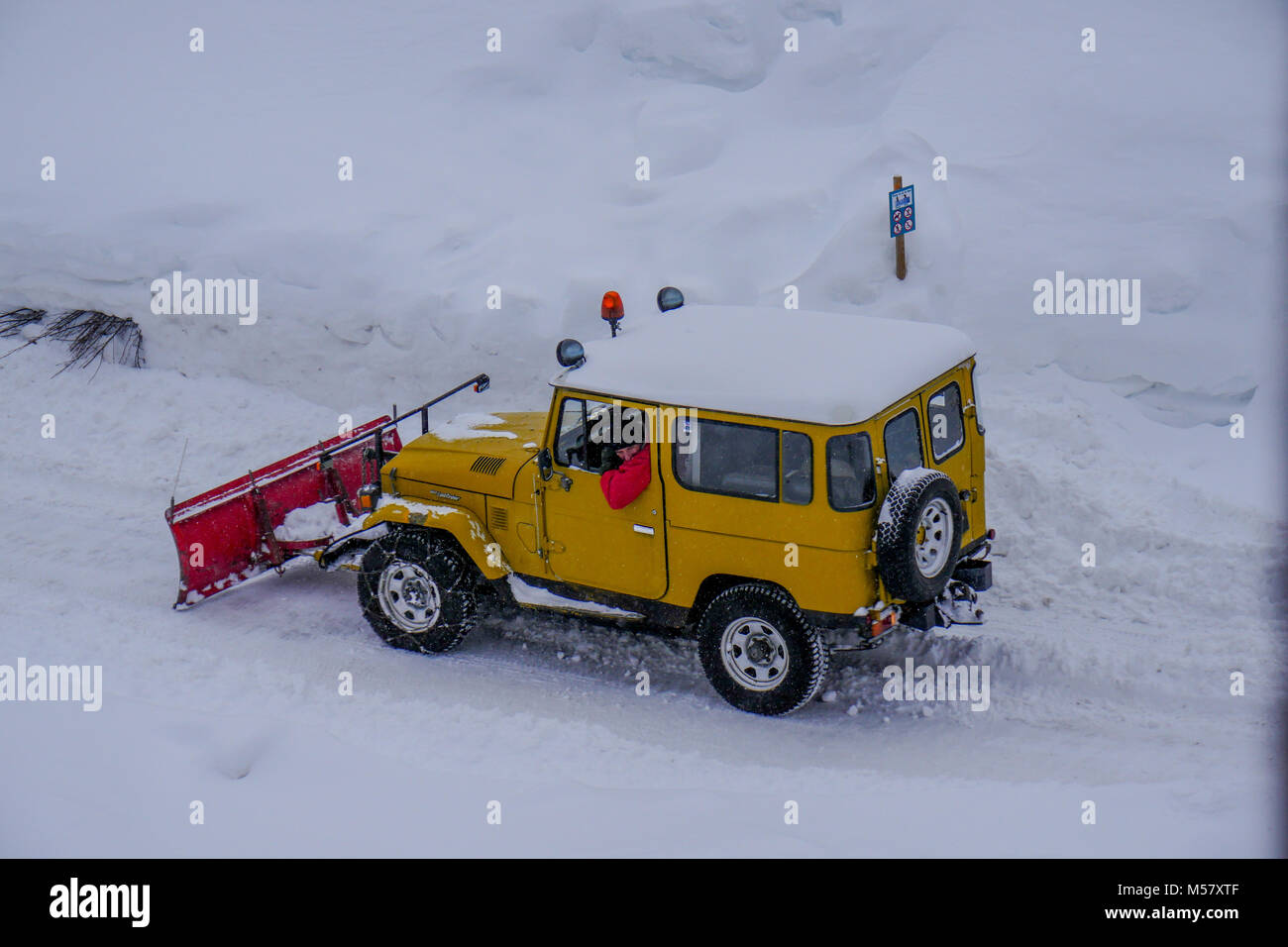 A Toyota Land Cruiser equiped with snow-plow cleans a road covered with ...