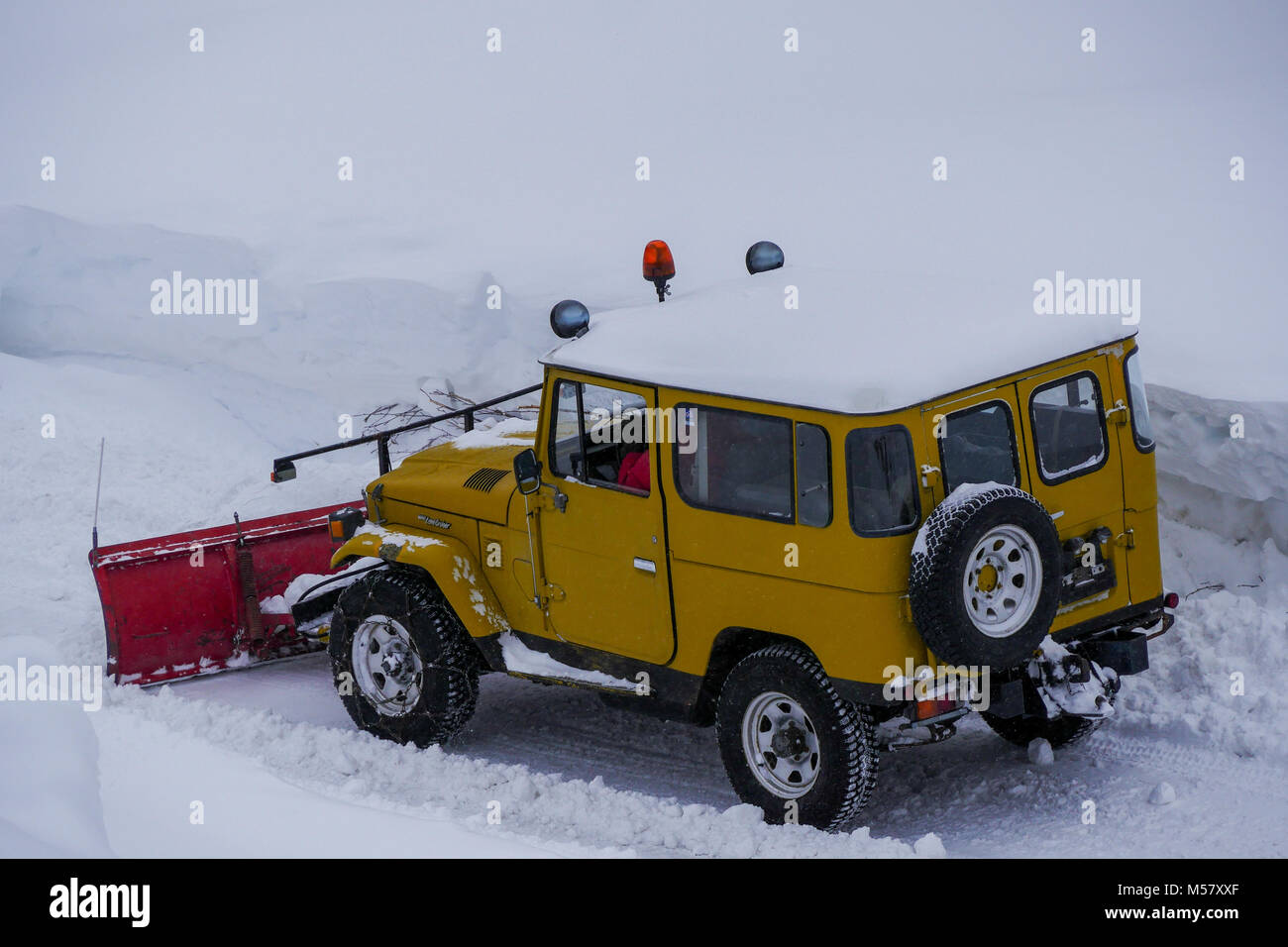 A Toyota Land Cruiser equiped with snow-plow cleans a road covered with ...