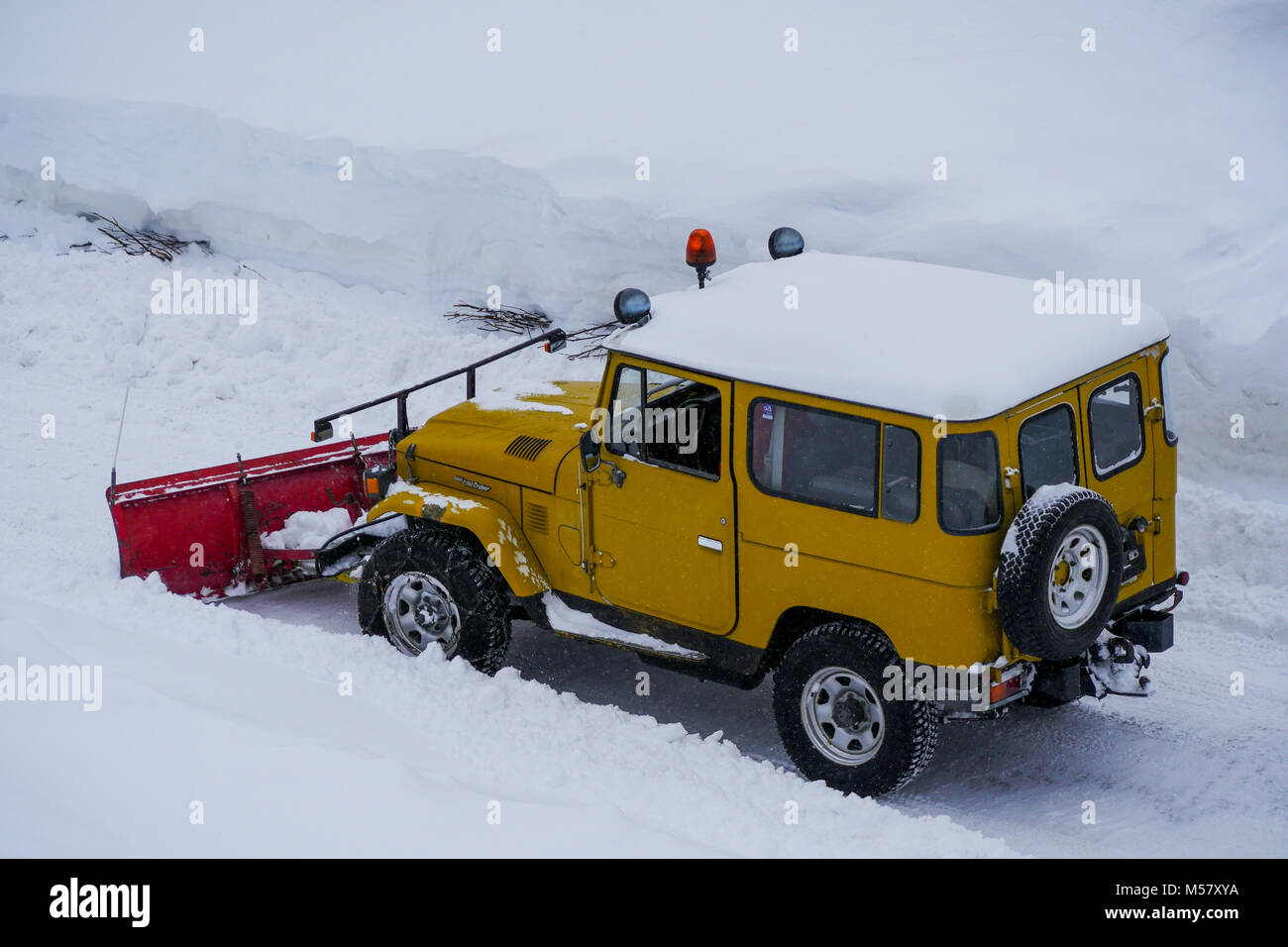 A Toyota Land Cruiser equiped with snow-plow cleans a road covered with ...