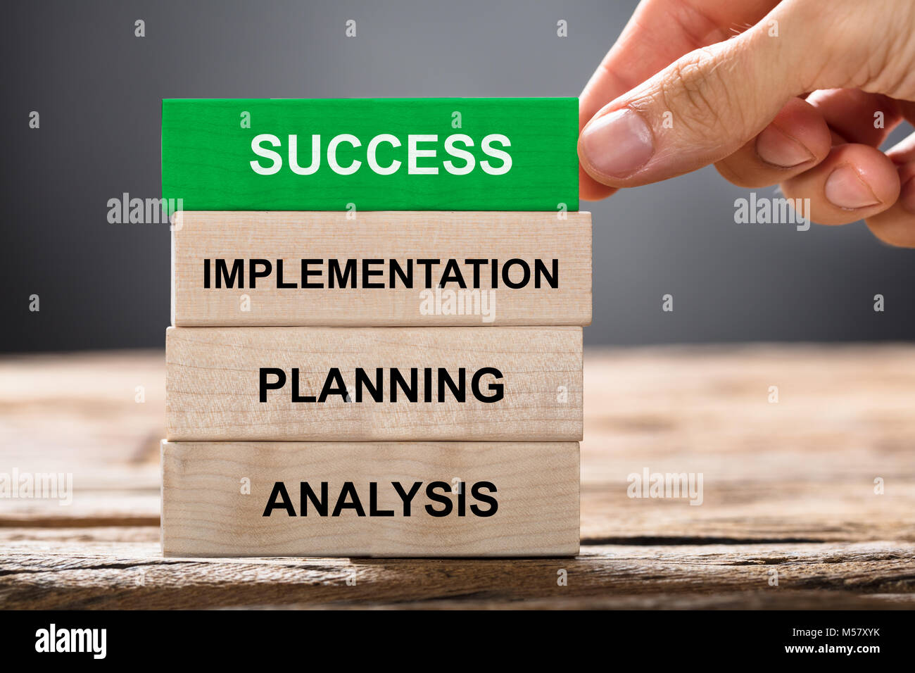 Closeup of hand building success concept with wooden blocks on wood ...