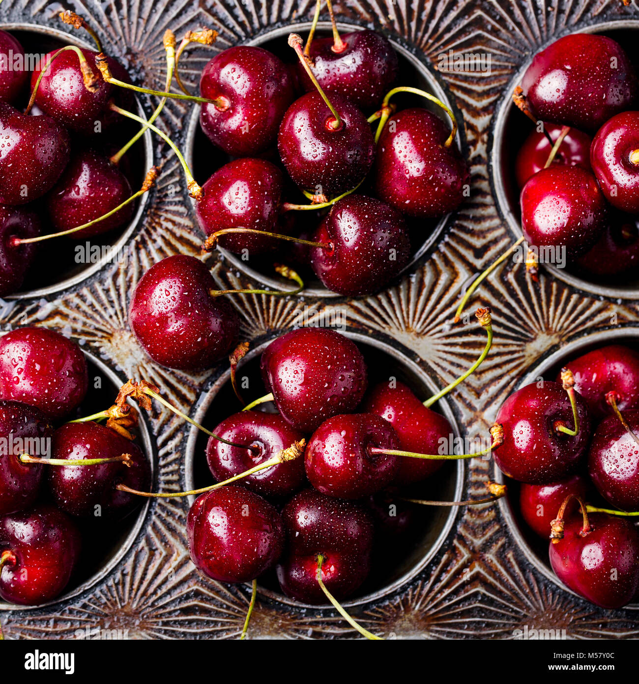 Fresh ripe black cherries in vintage backing dish on a stone background ...