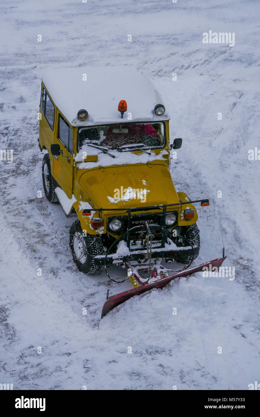 A Toyota Land Cruiser equiped with snow-plow cleans a road covered with ...