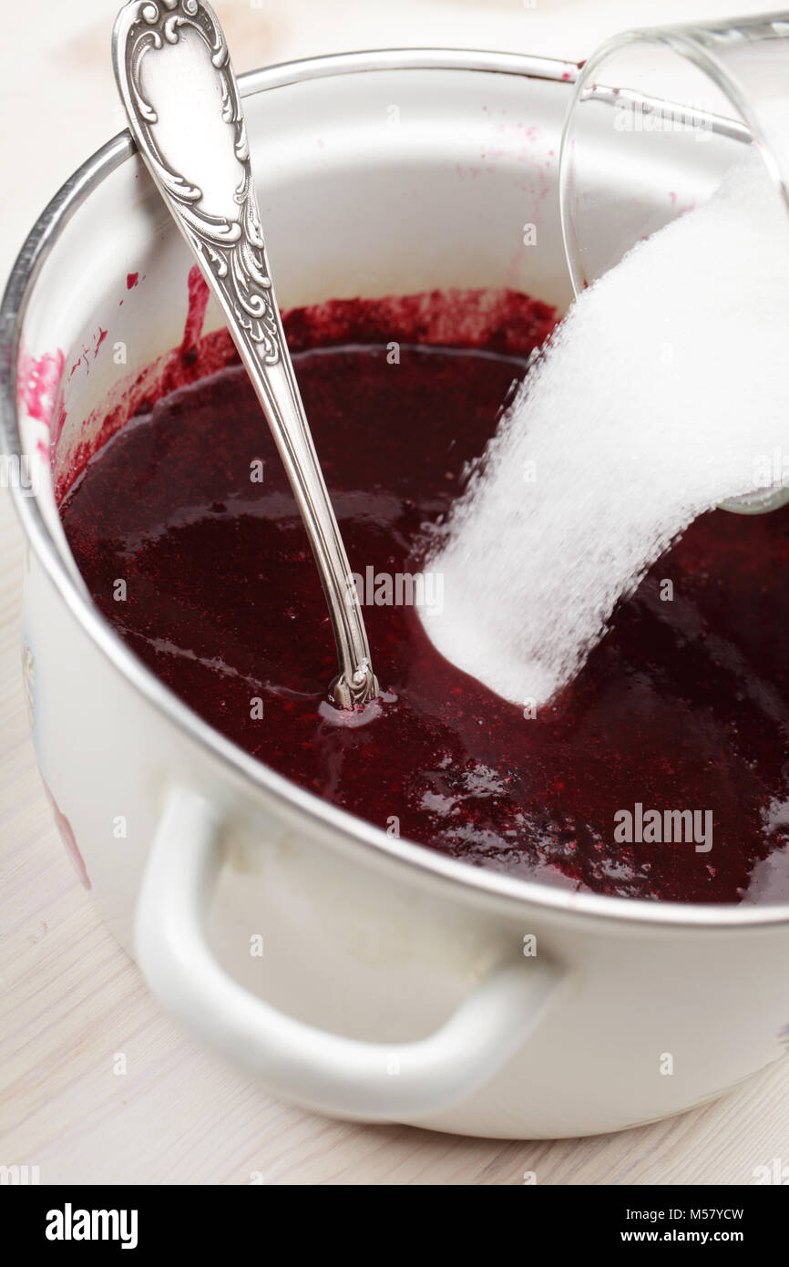 Pouring sugar into the pan with black currant syrup Stock Photo - Alamy