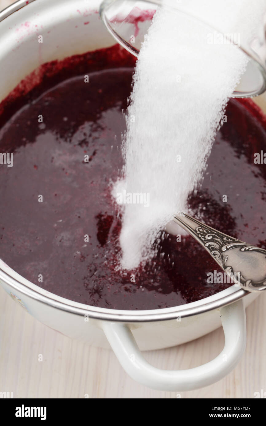 Pouring sugar into the pan with black currant syrup Stock Photo - Alamy