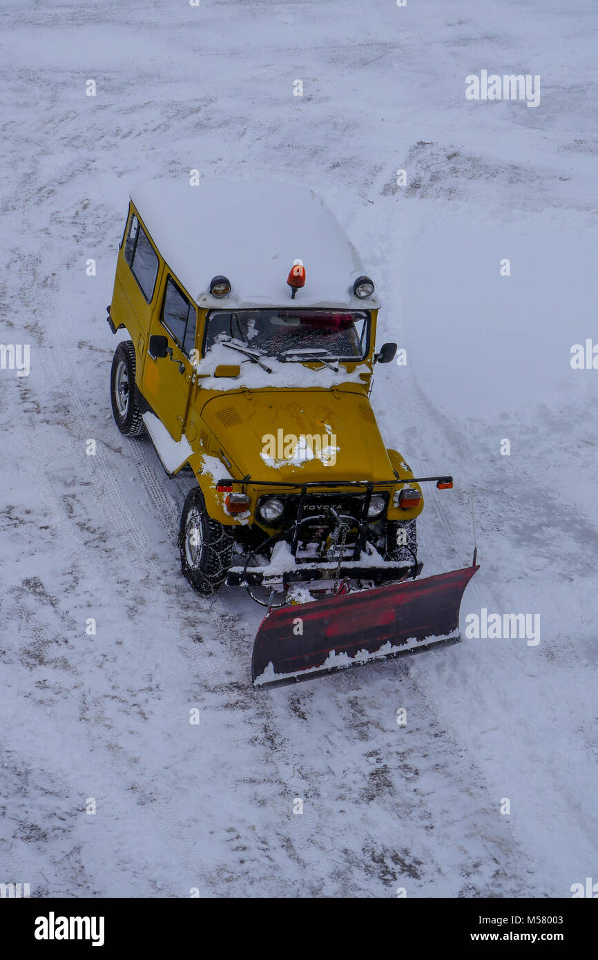 A Toyota Land Cruiser equiped with snow-plow cleans a road covered with ...