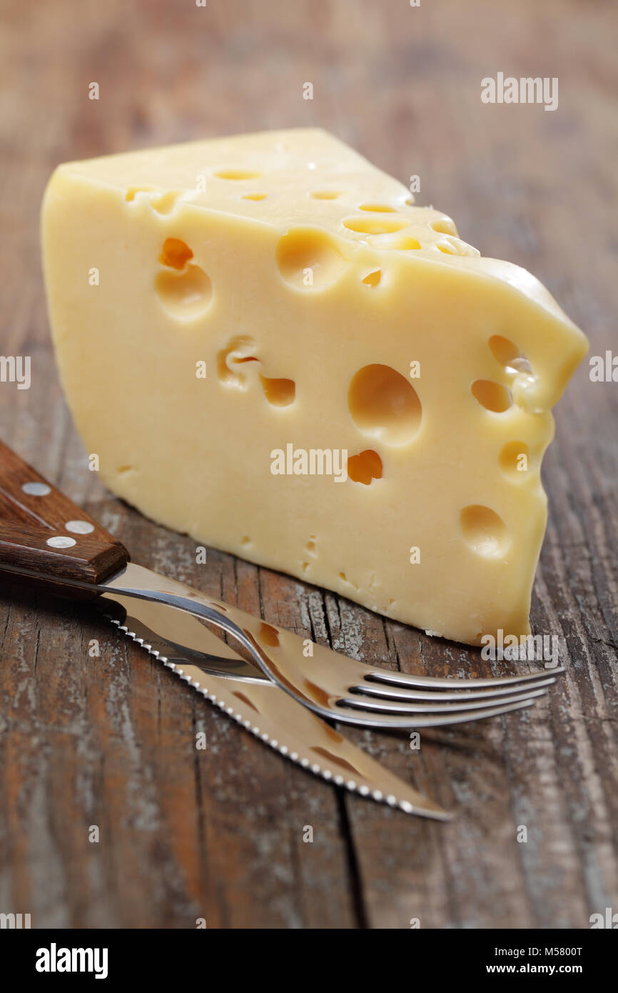 Piece of yellow cheese with big holes Stock Photo - Alamy