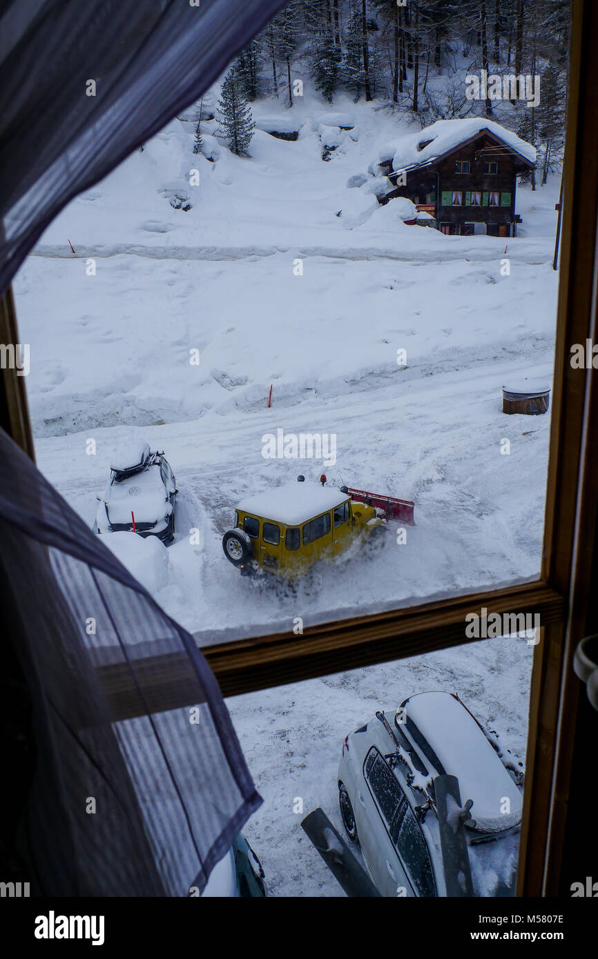 Car driving in winter: a snow plow at work in a car park covered with ...