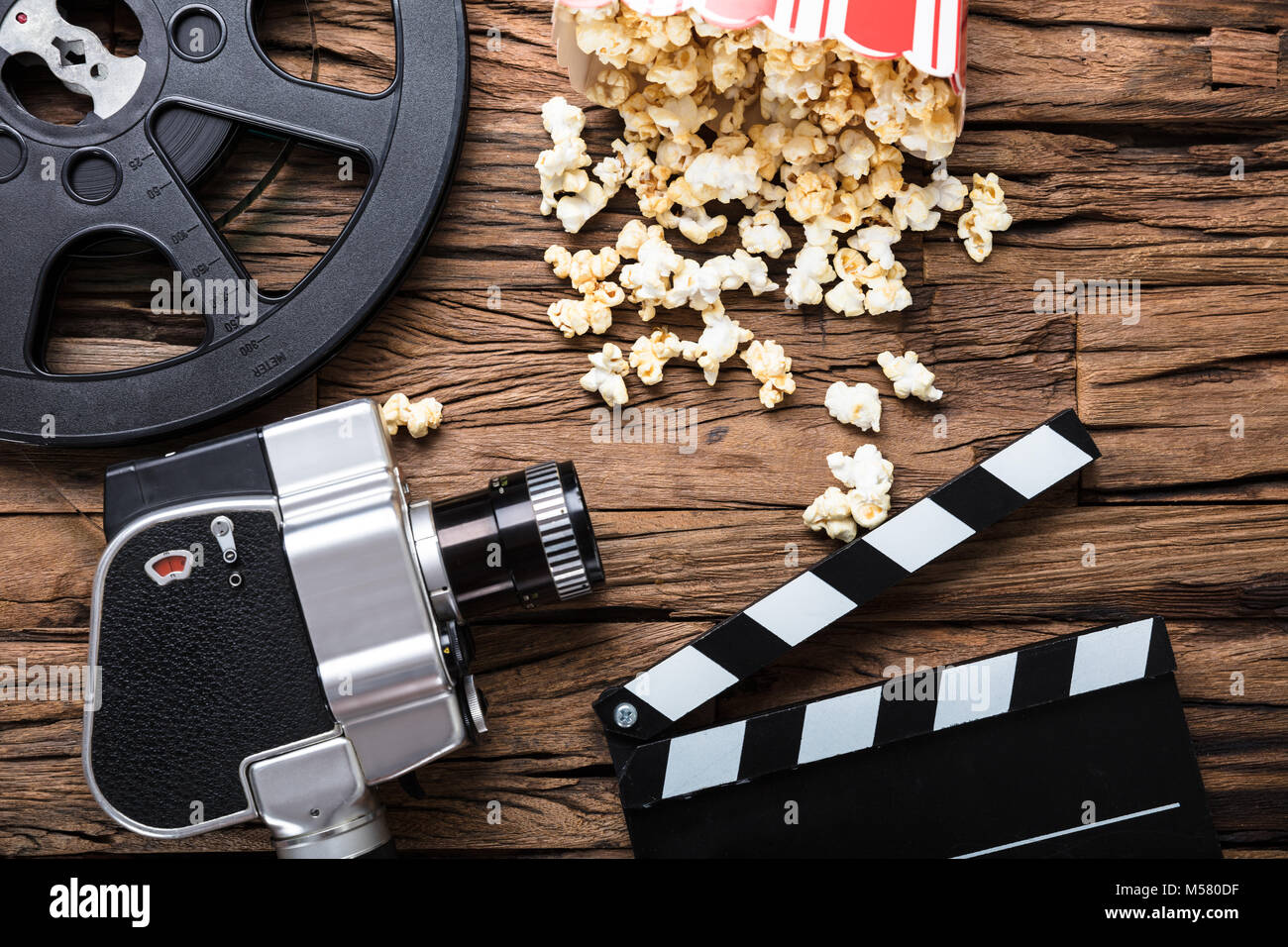 Closeup of movie camera with film reel clapper board and popcorn on ...
