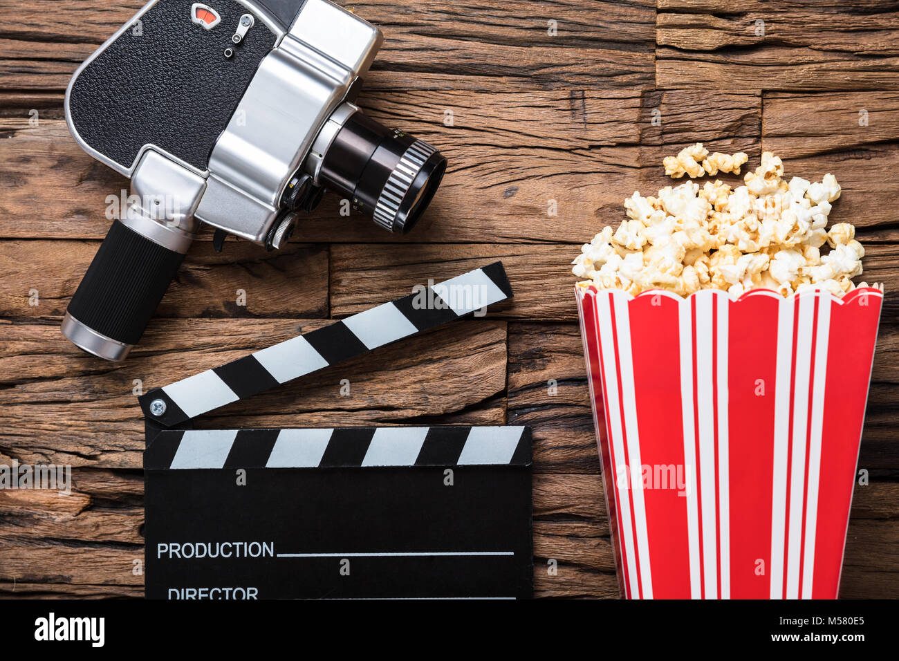 Closeup of movie camera with clapper board and popcorn on wood Stock ...