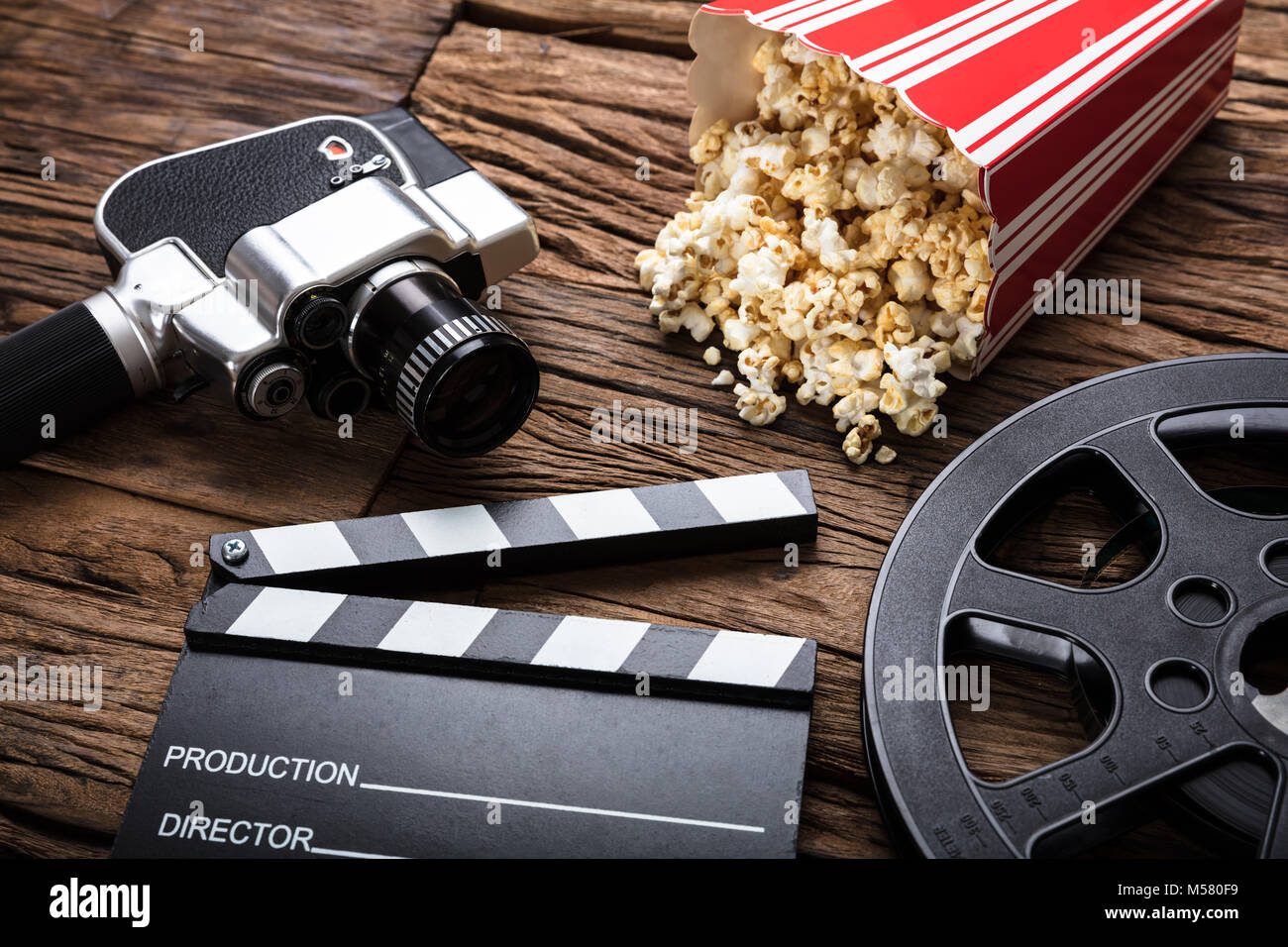 Closeup of movie camera with clapper board and popcorn on wood Stock ...