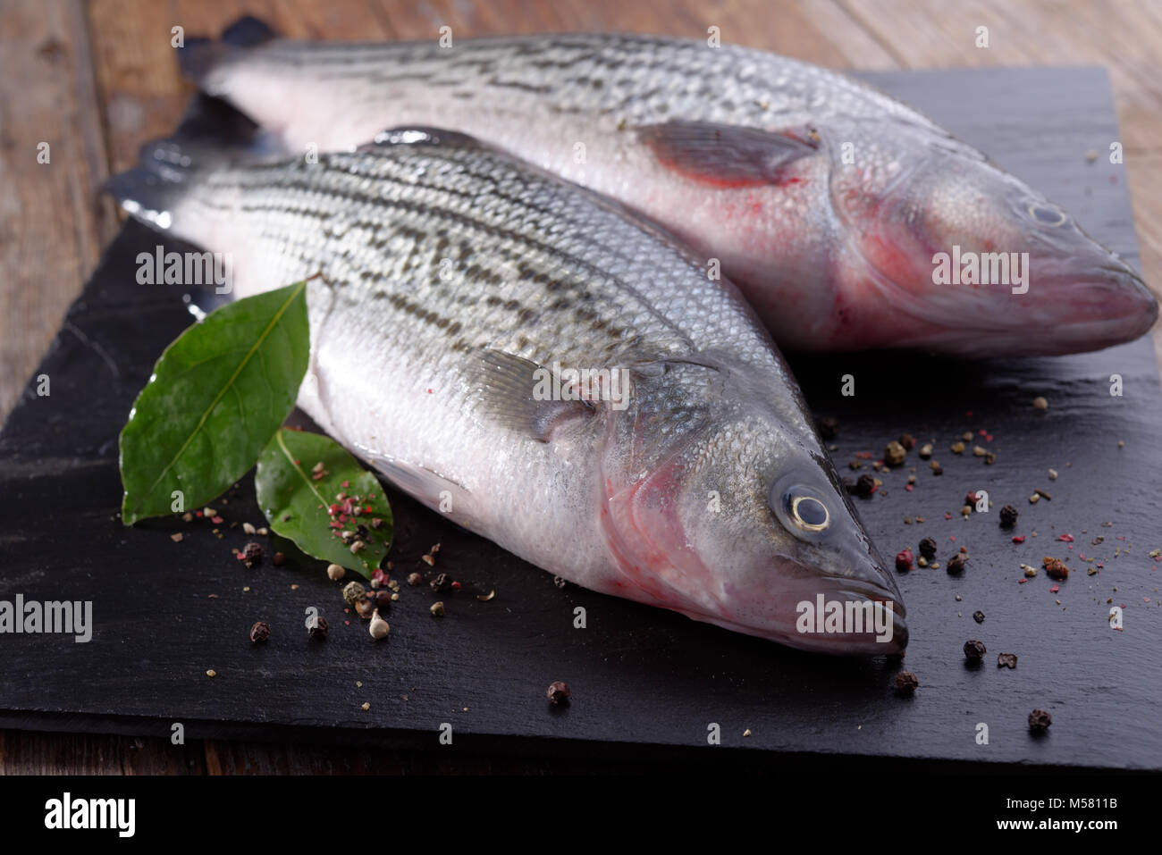Raw sunshine bass fish with spices on a table Stock Photo - Alamy