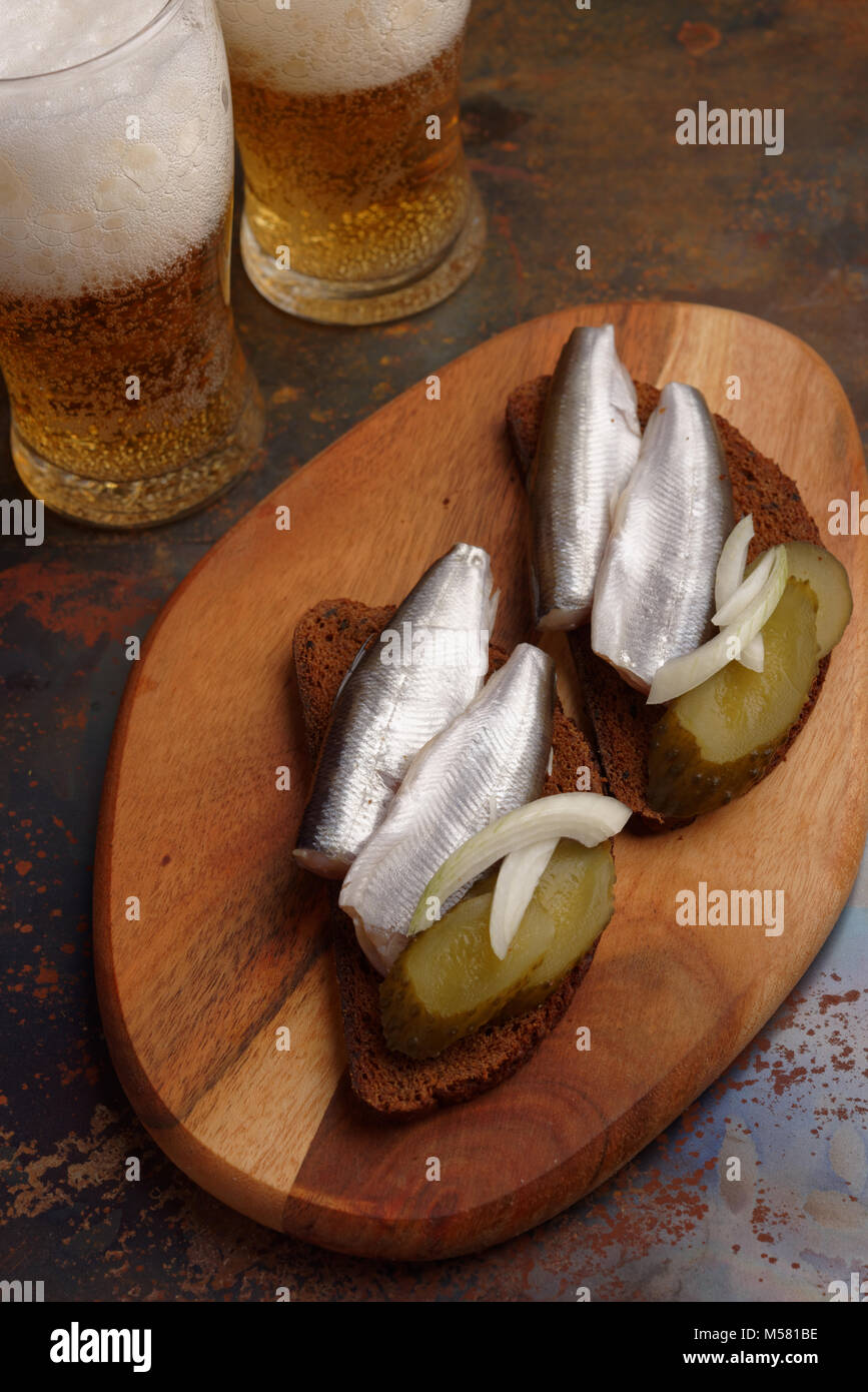 Two sandwiches with salt smelt fish, pickles, onion, and two glasses of ...