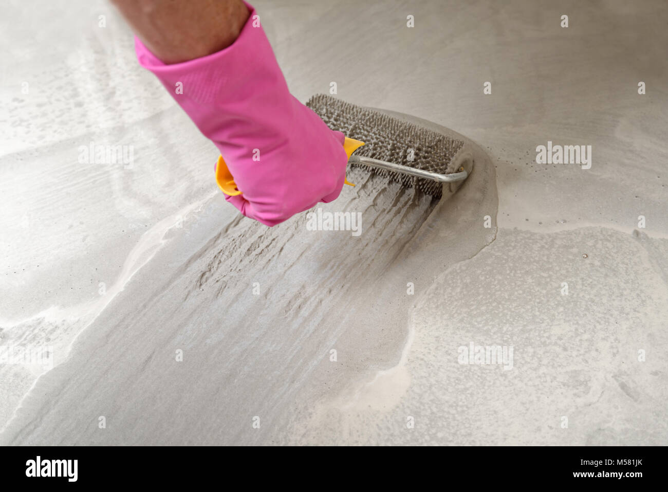 Leveling the floor using spiked roller Stock Photo - Alamy