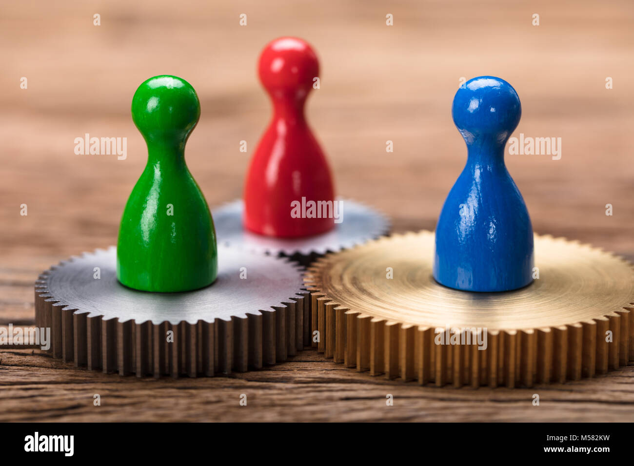 Closeup of colorful pawn figurines on cogwheels on wooden table Stock ...