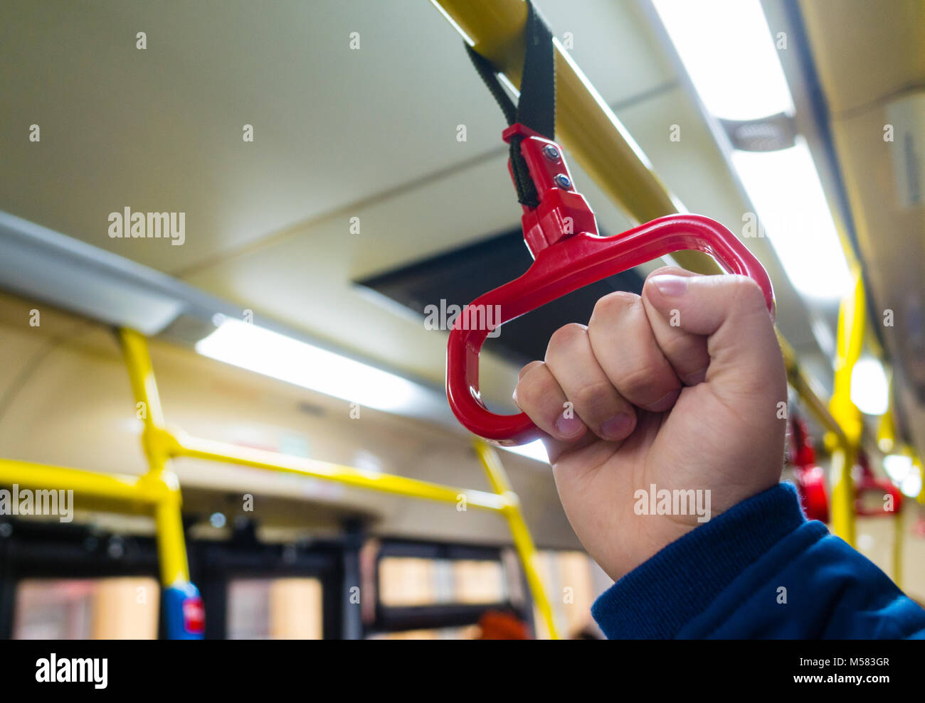 The man's hand holds onto the red handle of the handrail in public ...