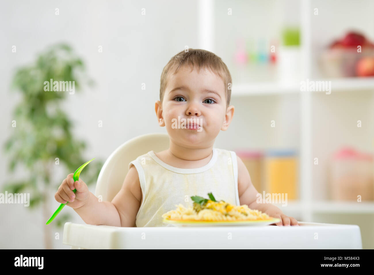 funny baby eating healthy food in kitchen Stock Photo - Alamy