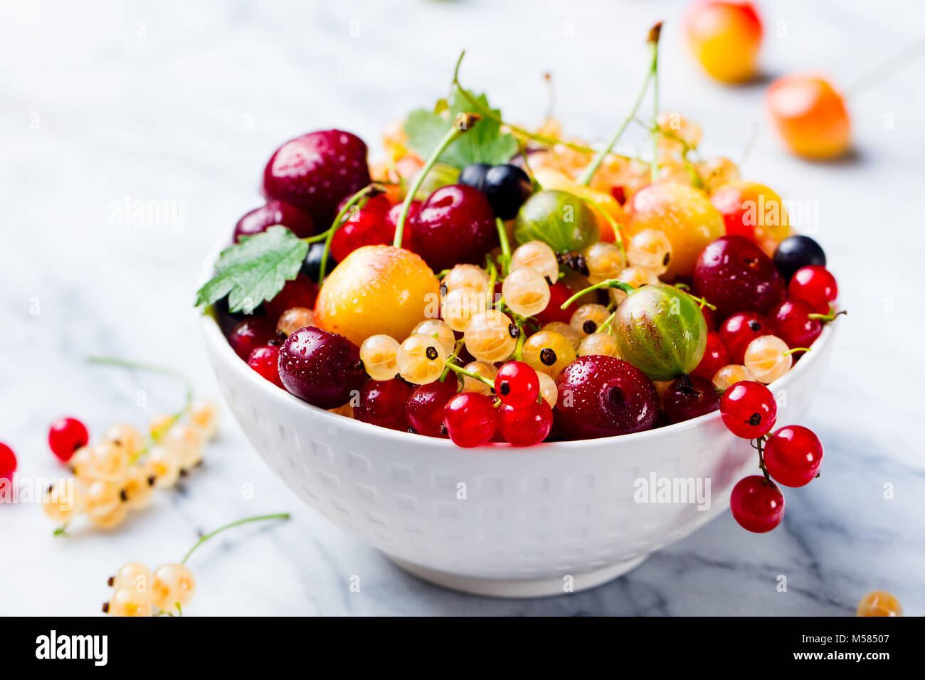 Assortment of fresh berries in white bowl. Marble background. Copy ...