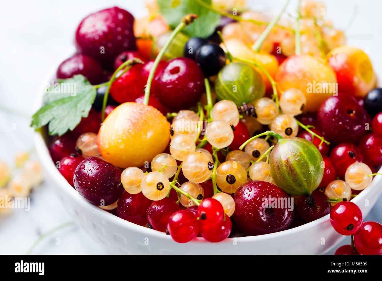 Assortment of fresh berries in white bowl. Marble background Stock ...