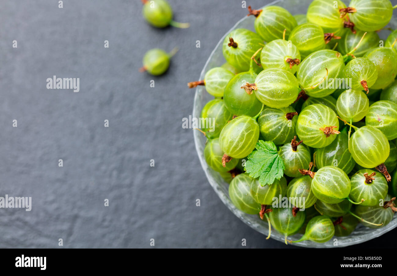 Gooseberries in glass bowl on black stone slate background. Top view ...