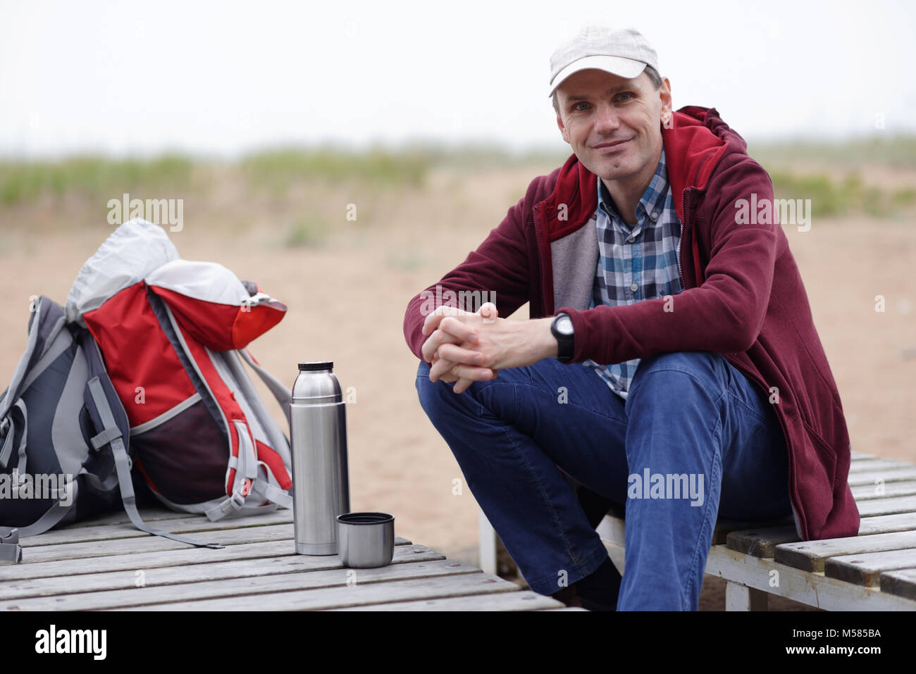 Man with backpack resting on a beach Stock Photo - Alamy