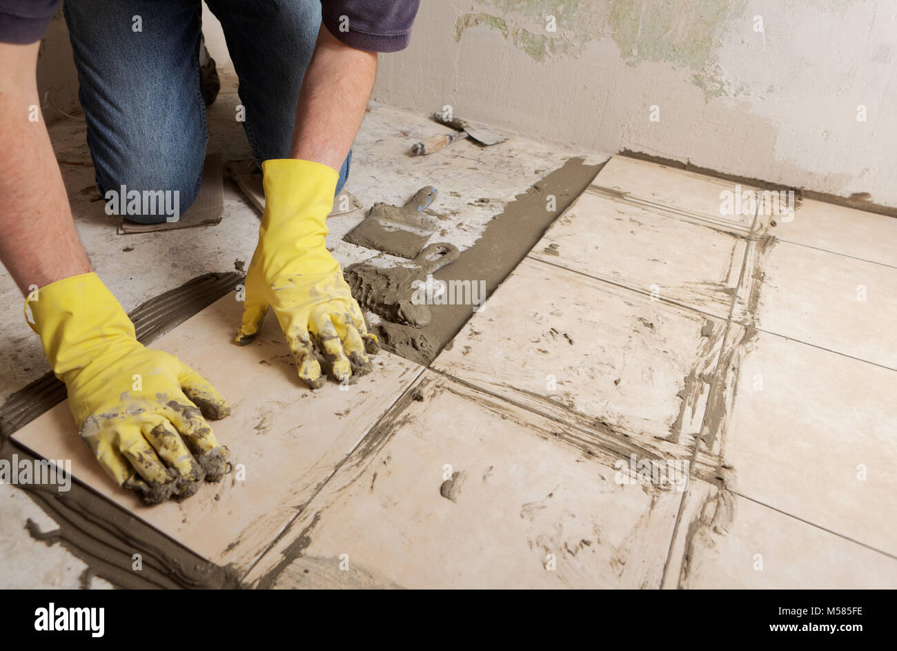 Tiler installs ceramic tiles on a floor Stock Photo - Alamy