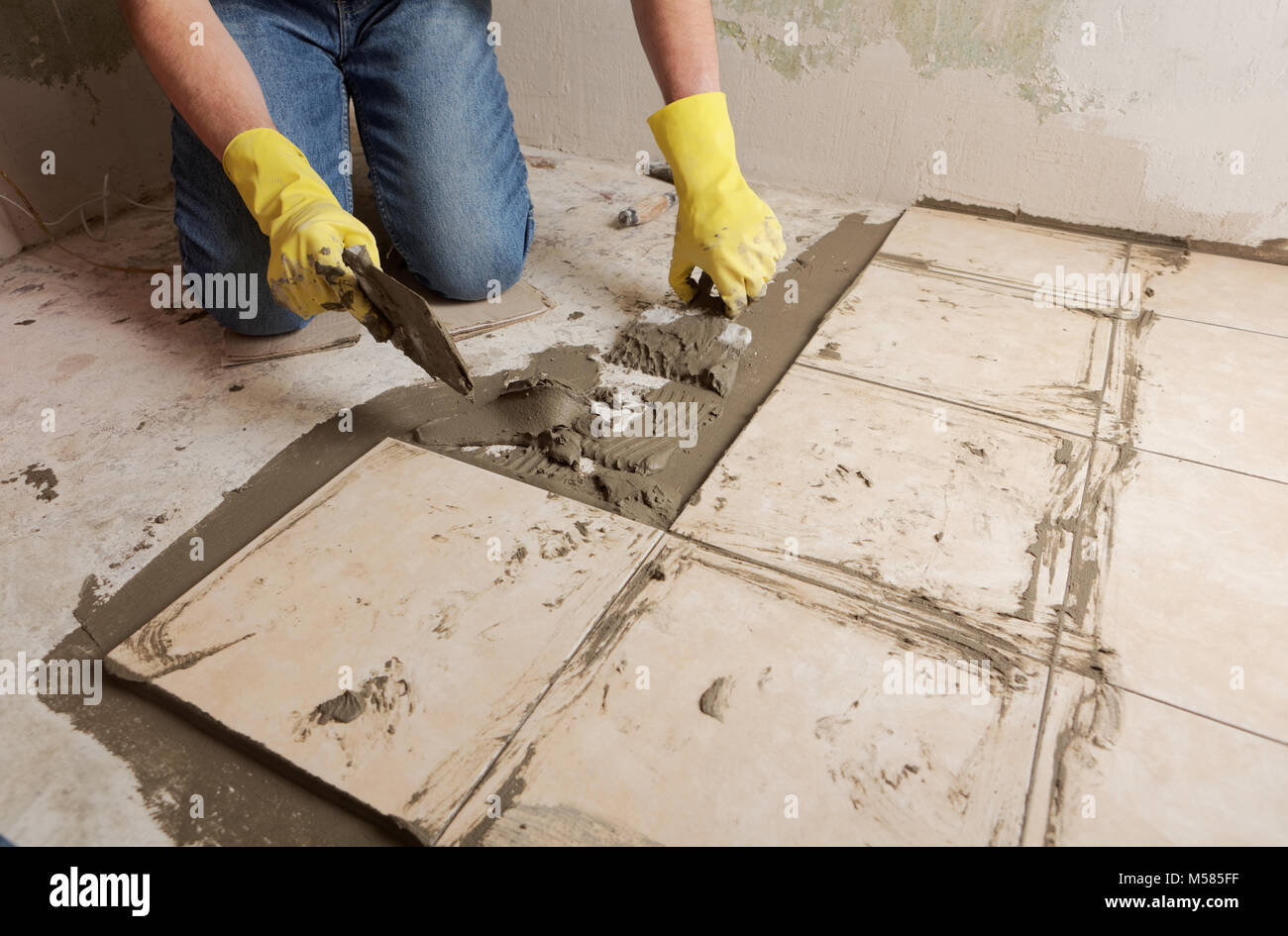 Tiler installs ceramic tiles on a floor Stock Photo - Alamy