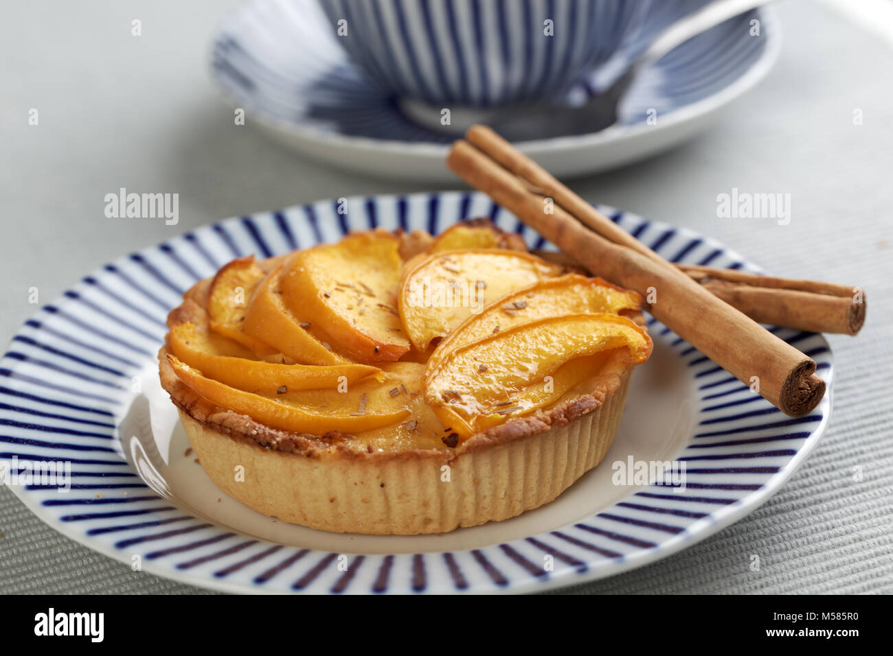 Peach tart and cinnamon sticks on a plate closeup Stock Photo - Alamy