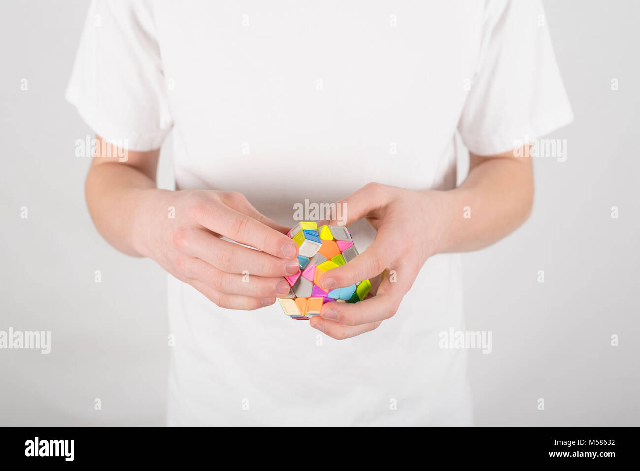 Teenage boy speed solving 12-sided dodecahedron puzzle in white T-shirt ...