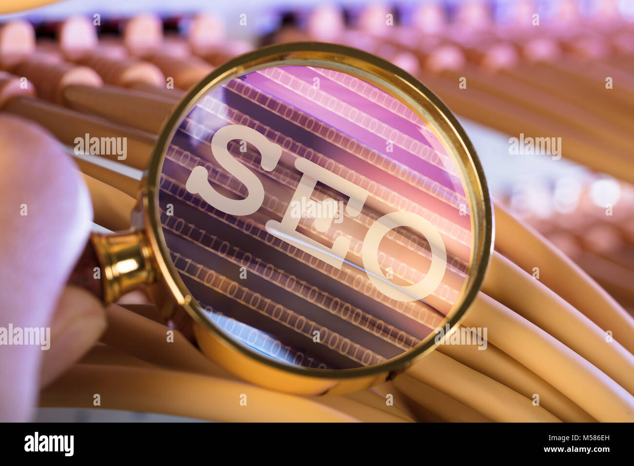 Cropped image of hand analyzing SEO through magnifying glass over ...