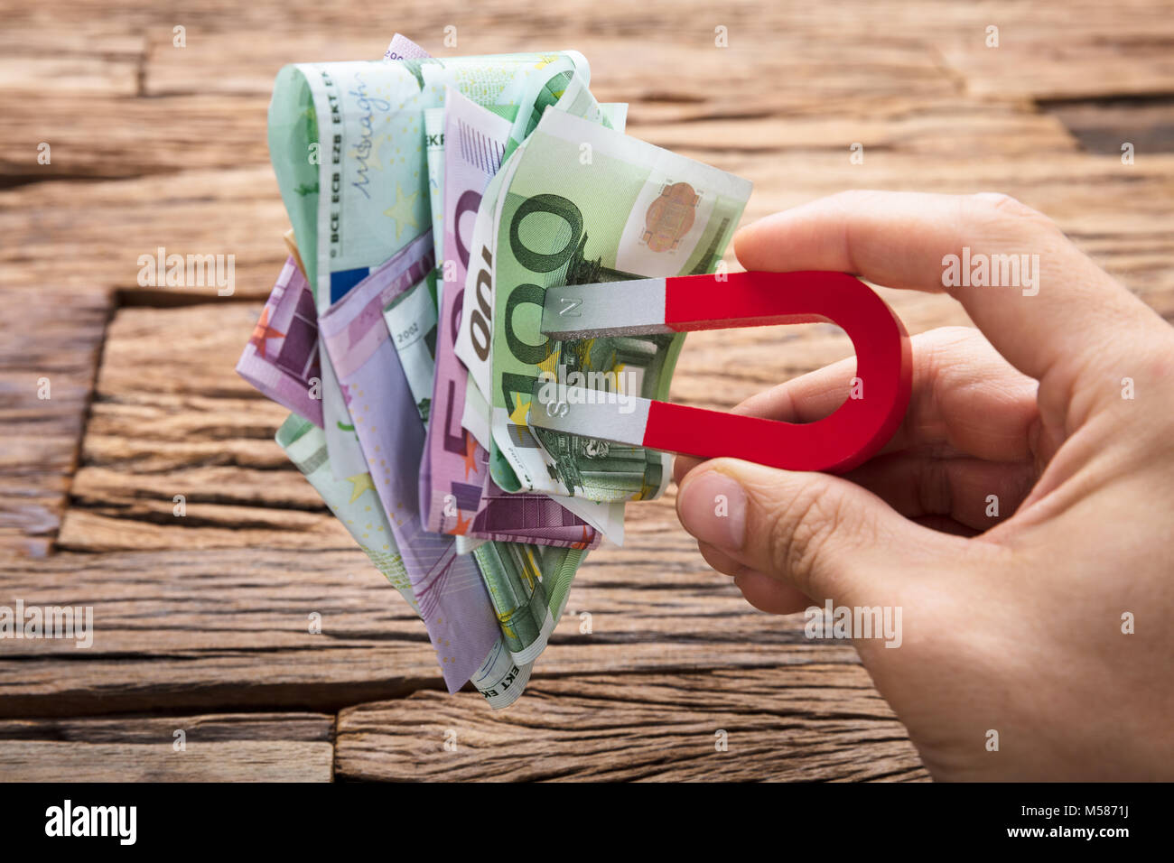 Cropped image of businessman's hand pulling euro papernotes with magnet ...