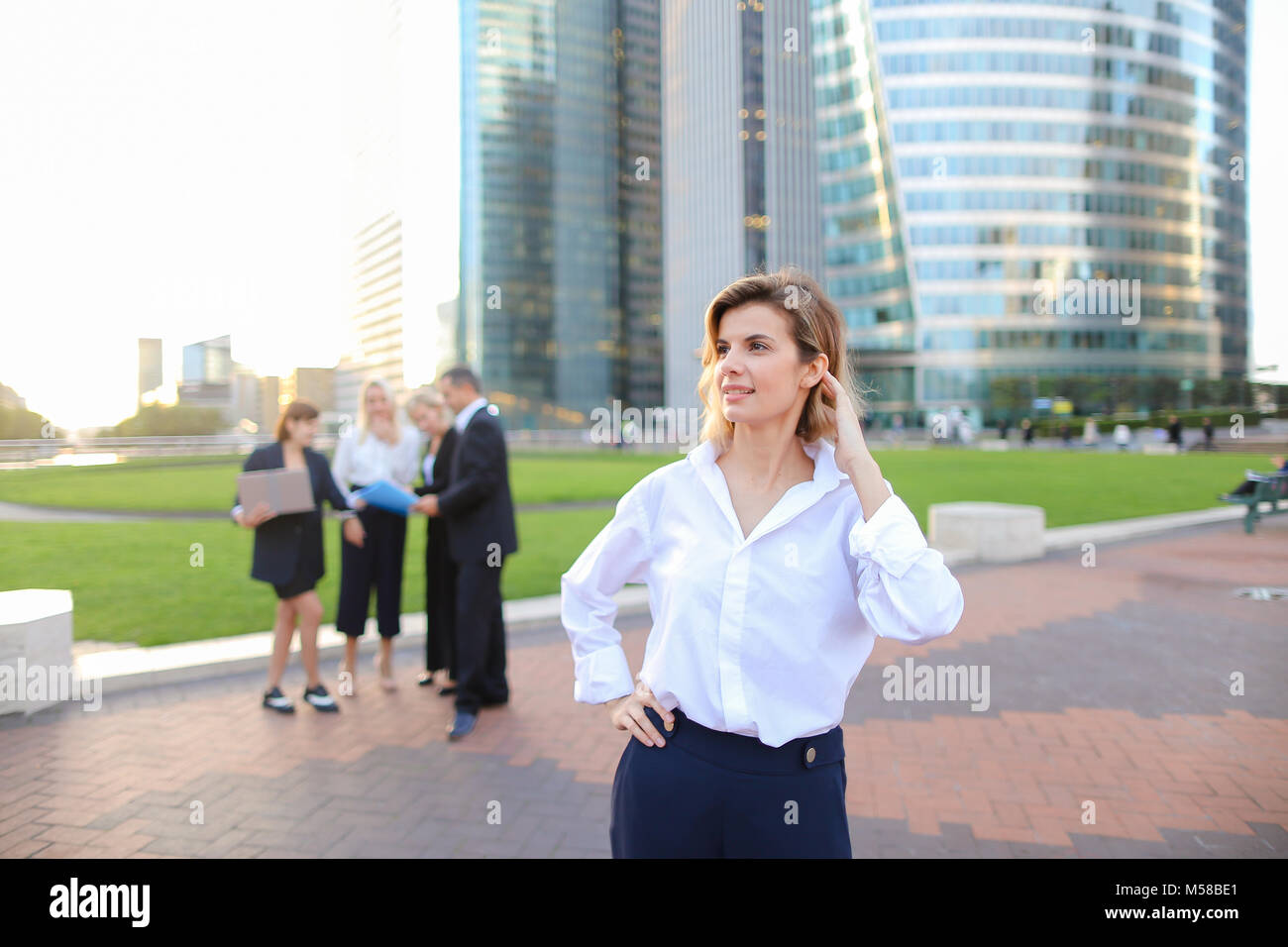 Secretary looking at camera with team members background in La D Stock ...